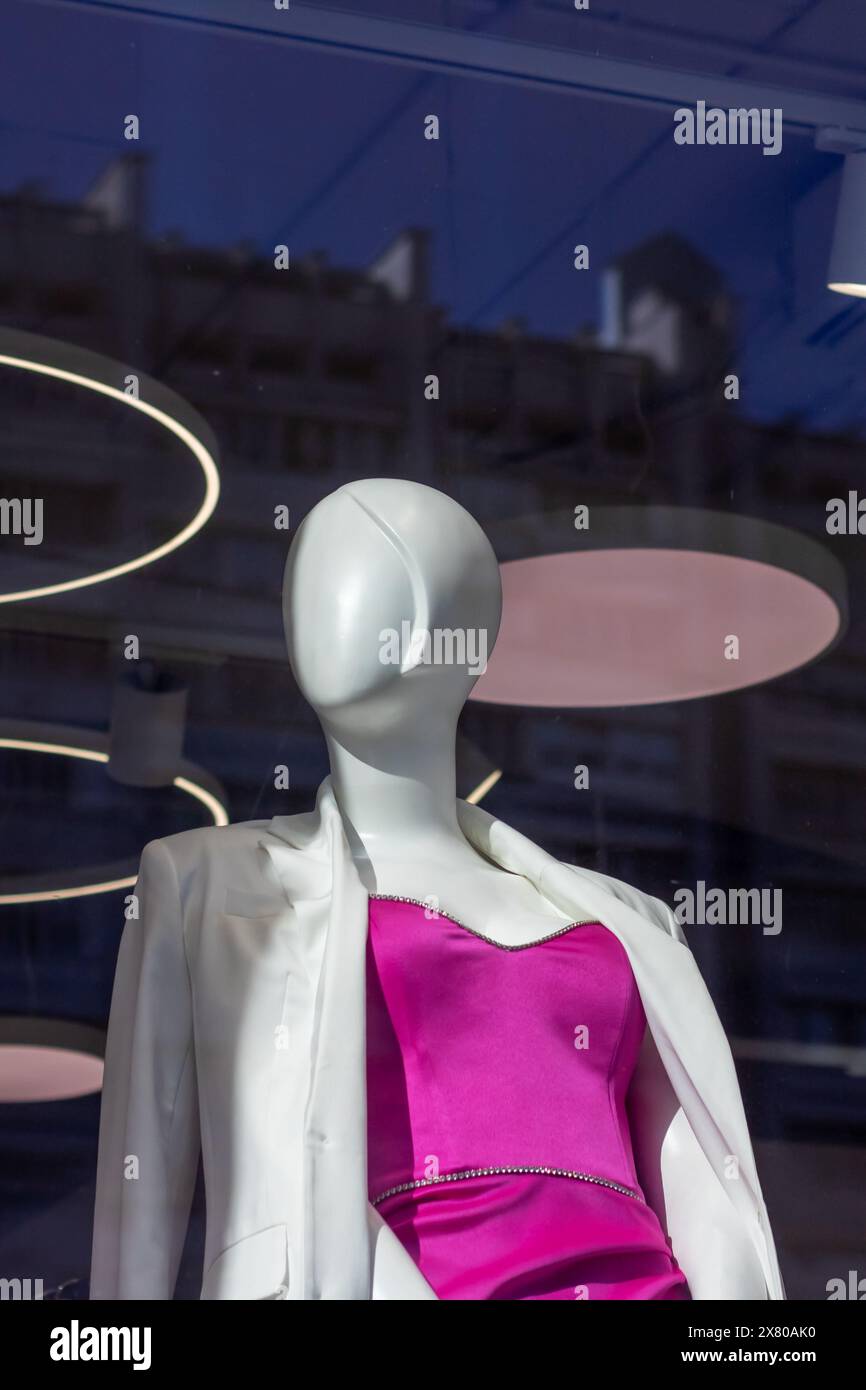 A mannequin is dressed in a pink dress and a white jacket, showcasing a ...