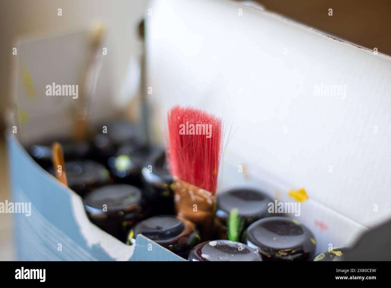 The box is full of jars of colorful paint and various brushes for ...