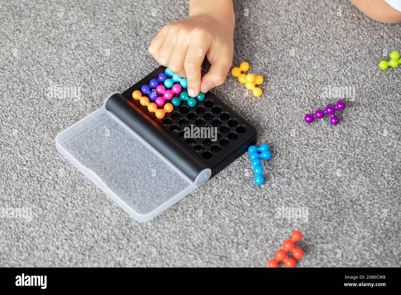 Child's hand piecing together a bead puzzle, enhancing fine motor ...