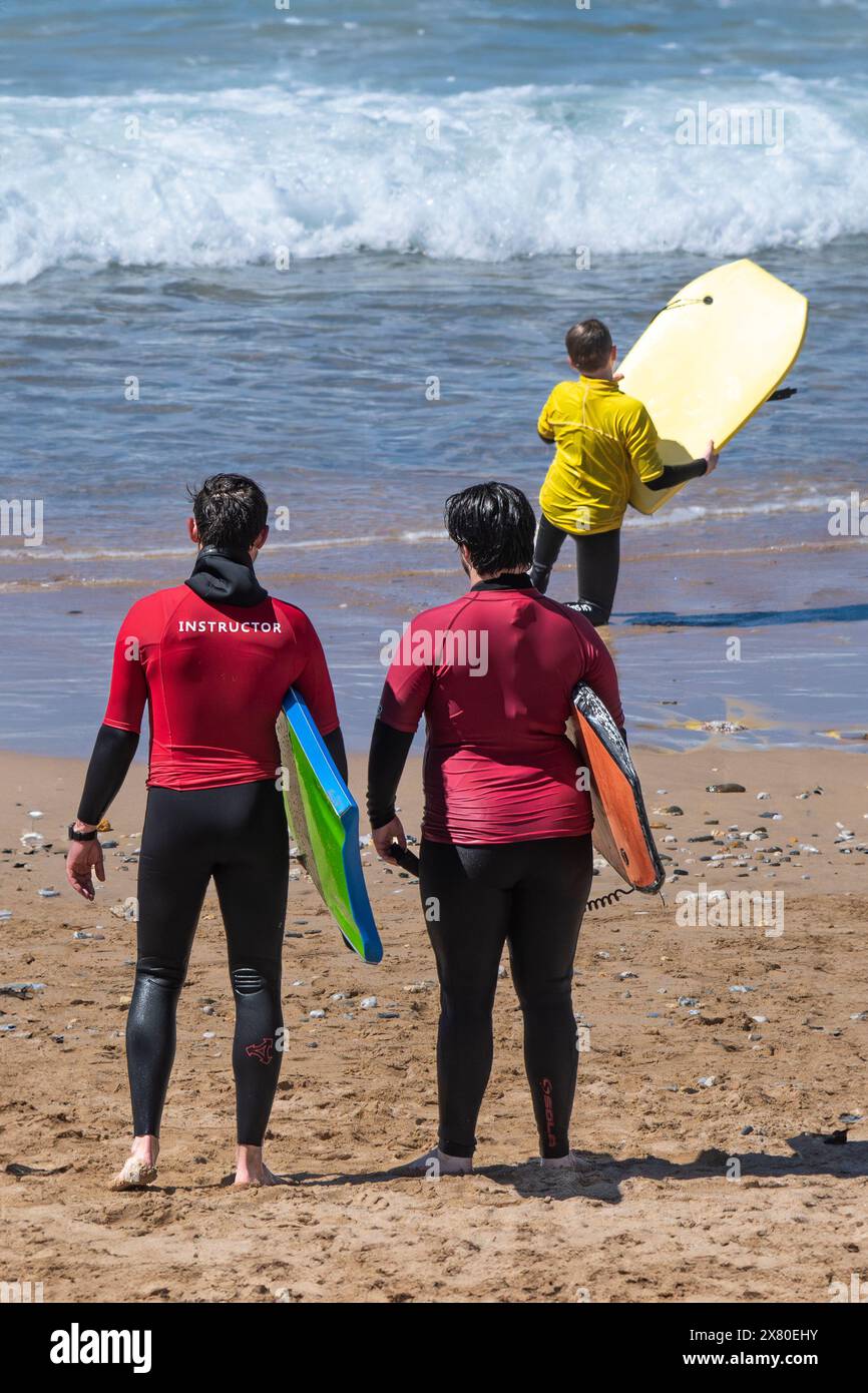 A surfing instructor with novices during a body boogie boarding lesson ...