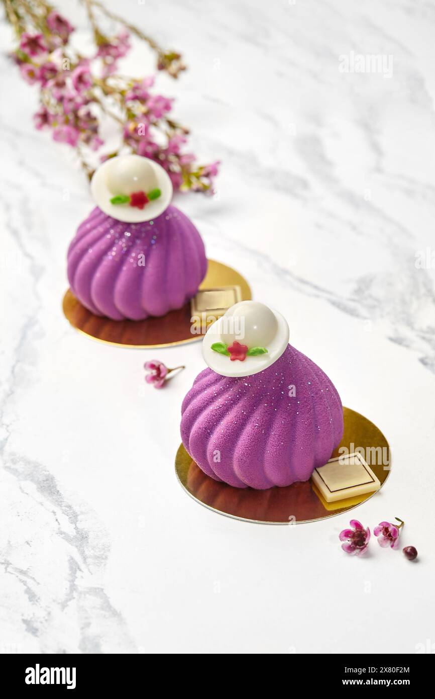 Purple mousse pastries crowned with chocolate caps against marble Stock ...