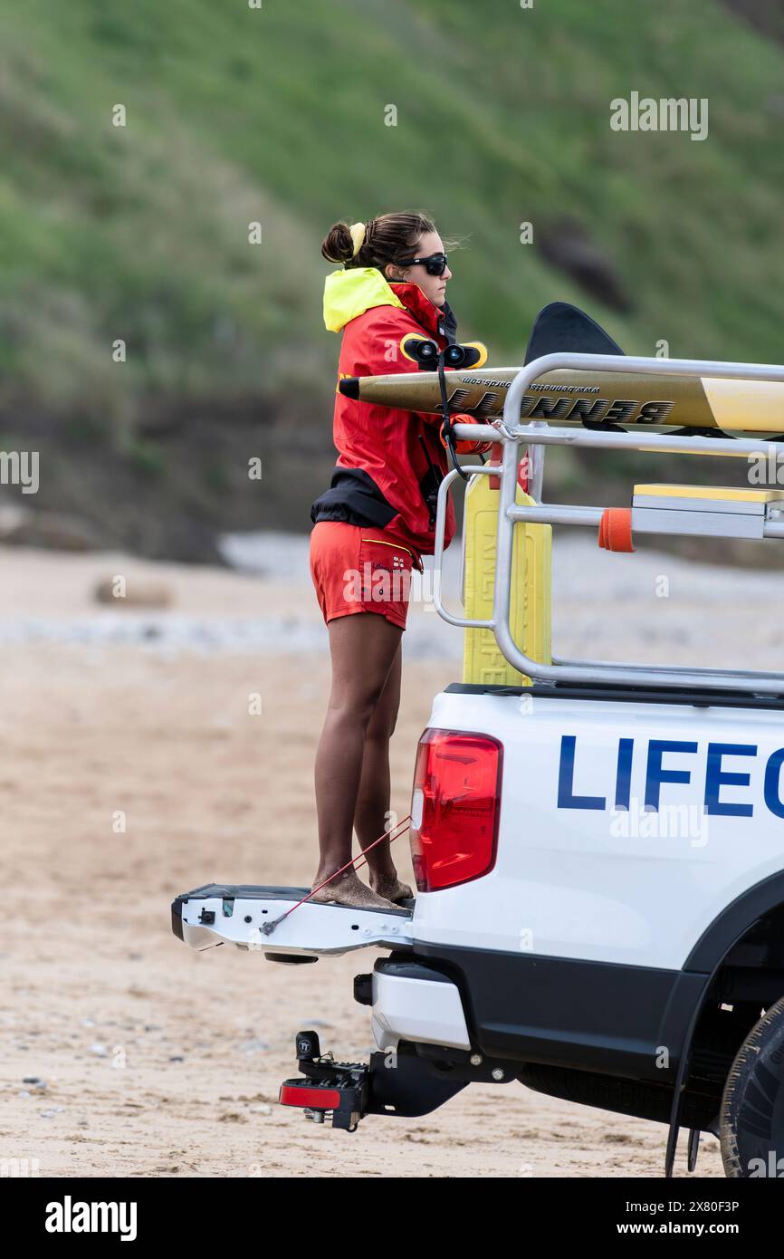 A female RNLI Lifeguard standing on the tailgate of the emergency ...