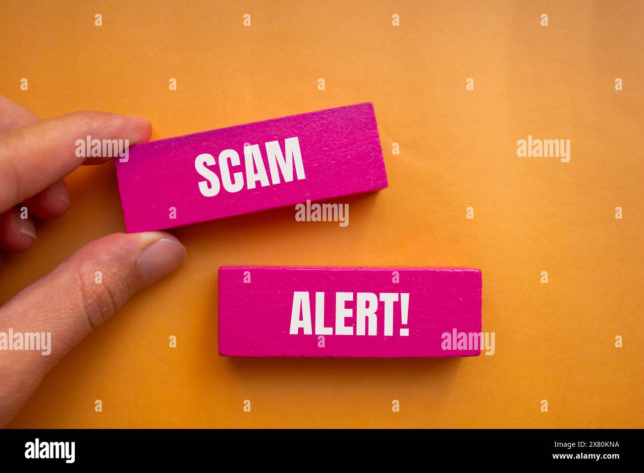 Scam alert words written on wooden pink blocks with orange background ...