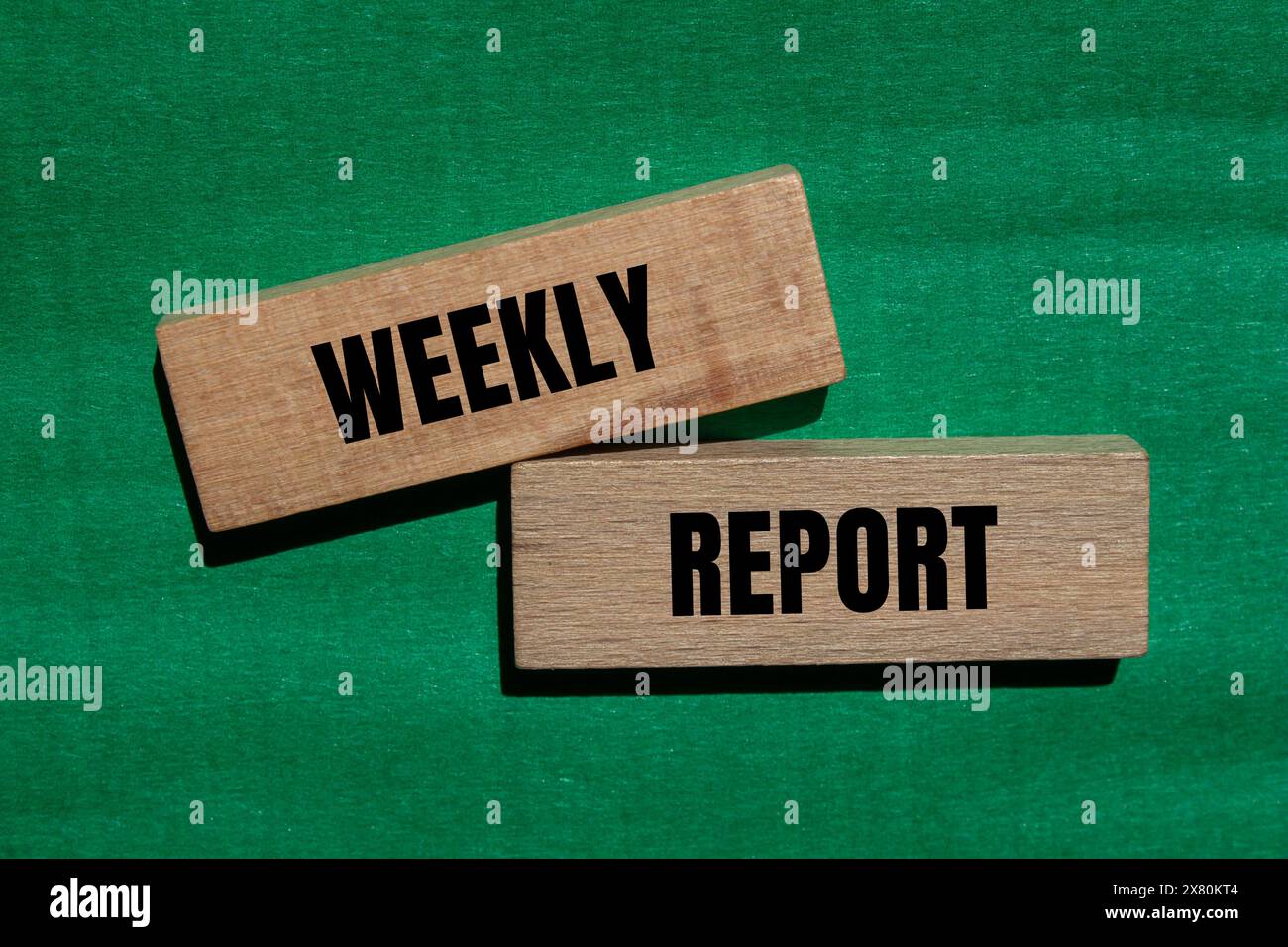 Weekly report words written on wooden blocks with green background ...