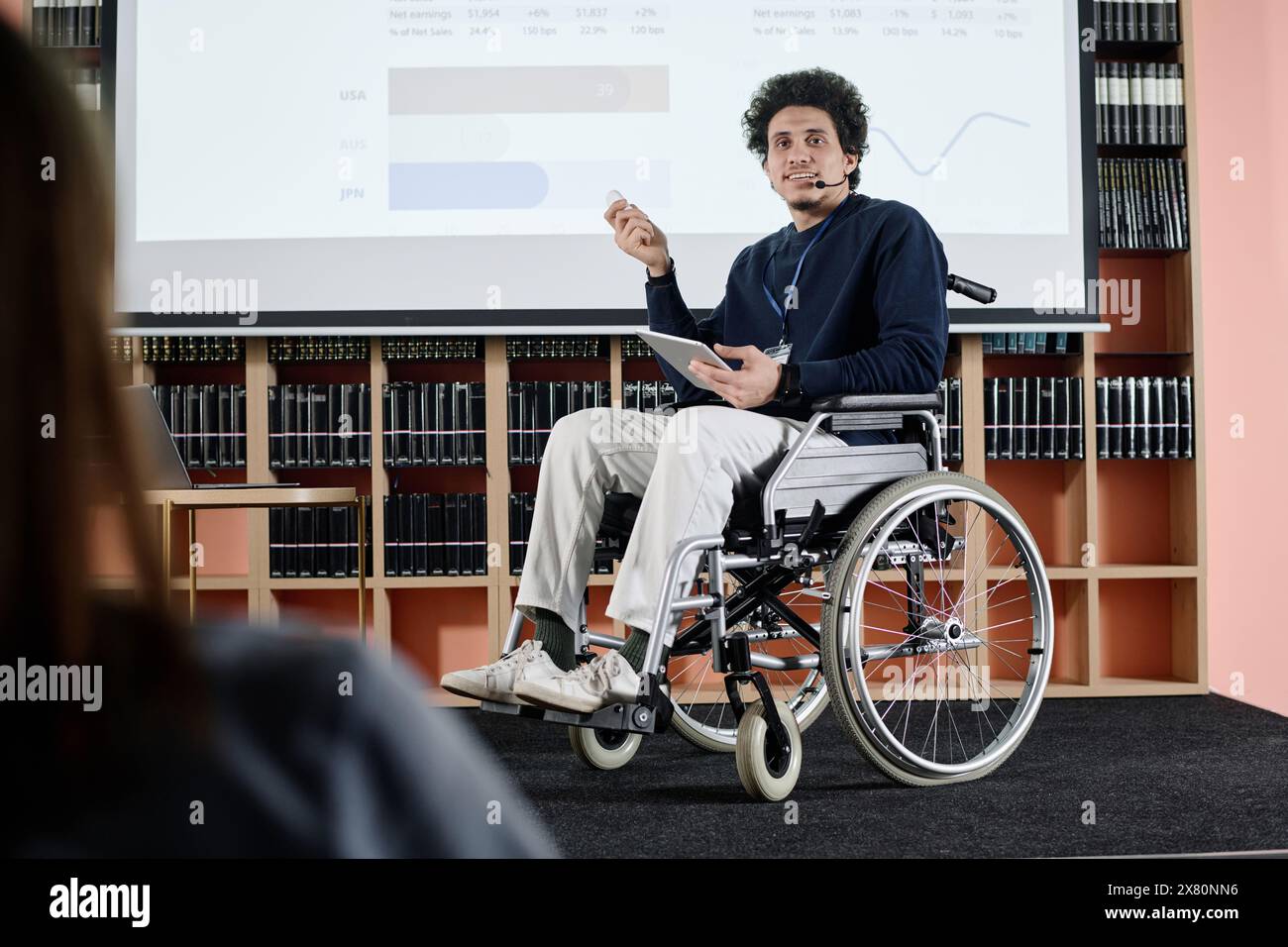 Over-the-shoulder shot of Middle Eastern student in wheelchair holding ...