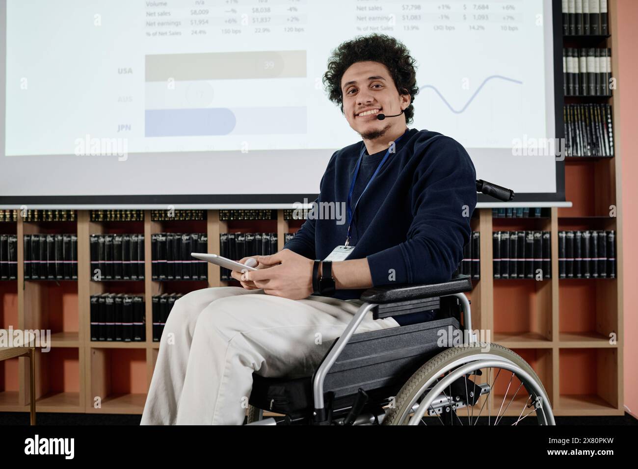 Portrait of cheerful young man with disability in wheelchair holding ...