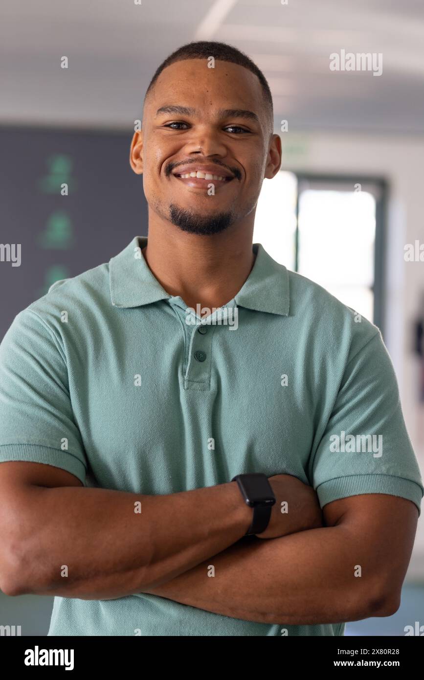 Biracial male physical therapist standing with arms crossed, smiling at ...