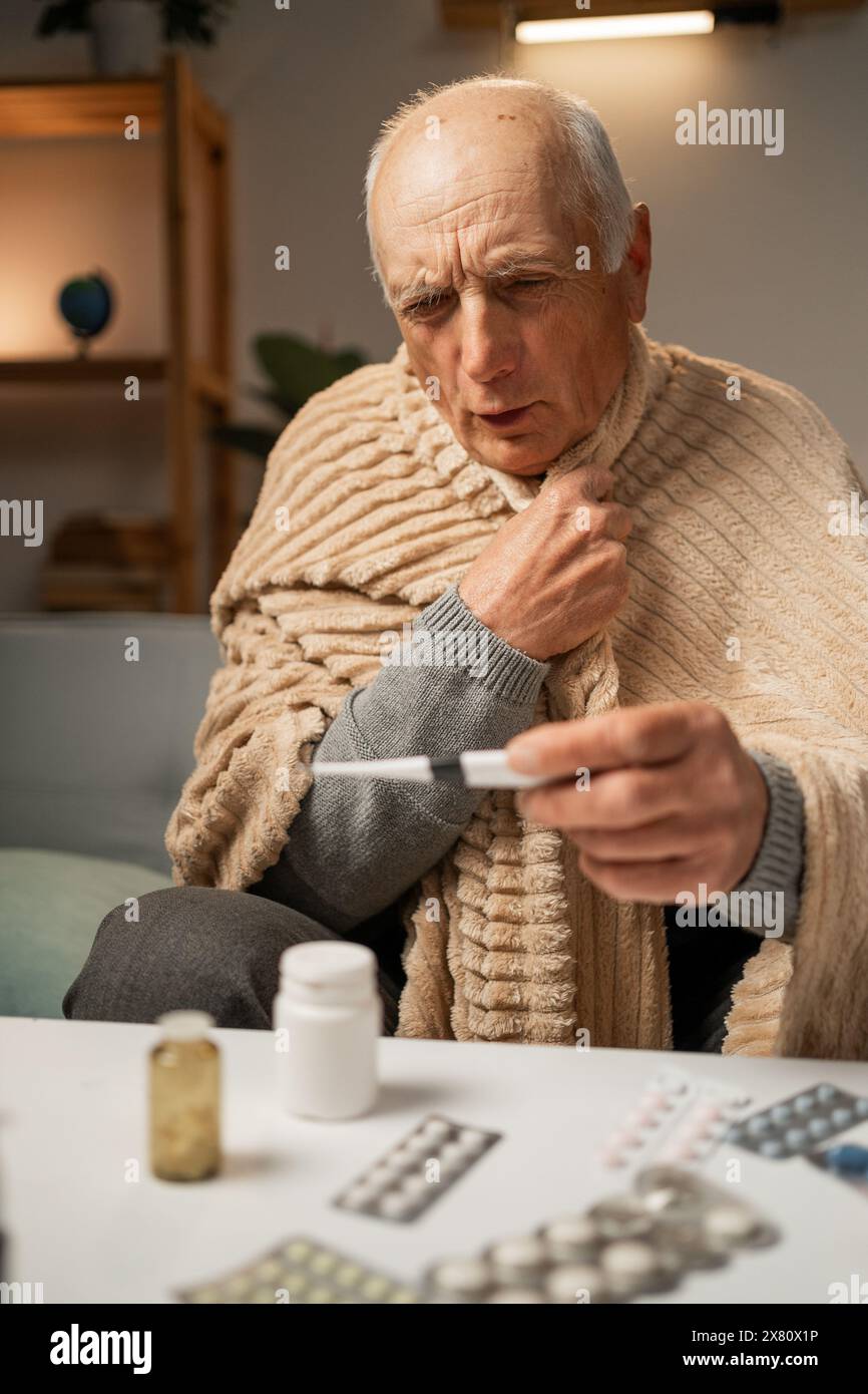 man holds thermometer. sick elderly man who takes thermometer and feels ...