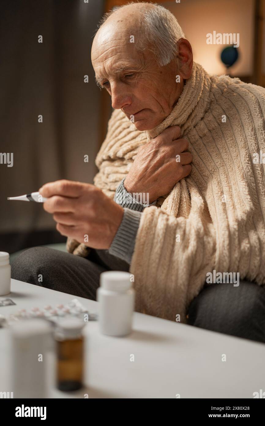 man holds thermometer. sick elderly man holding thermometer and feeling ...