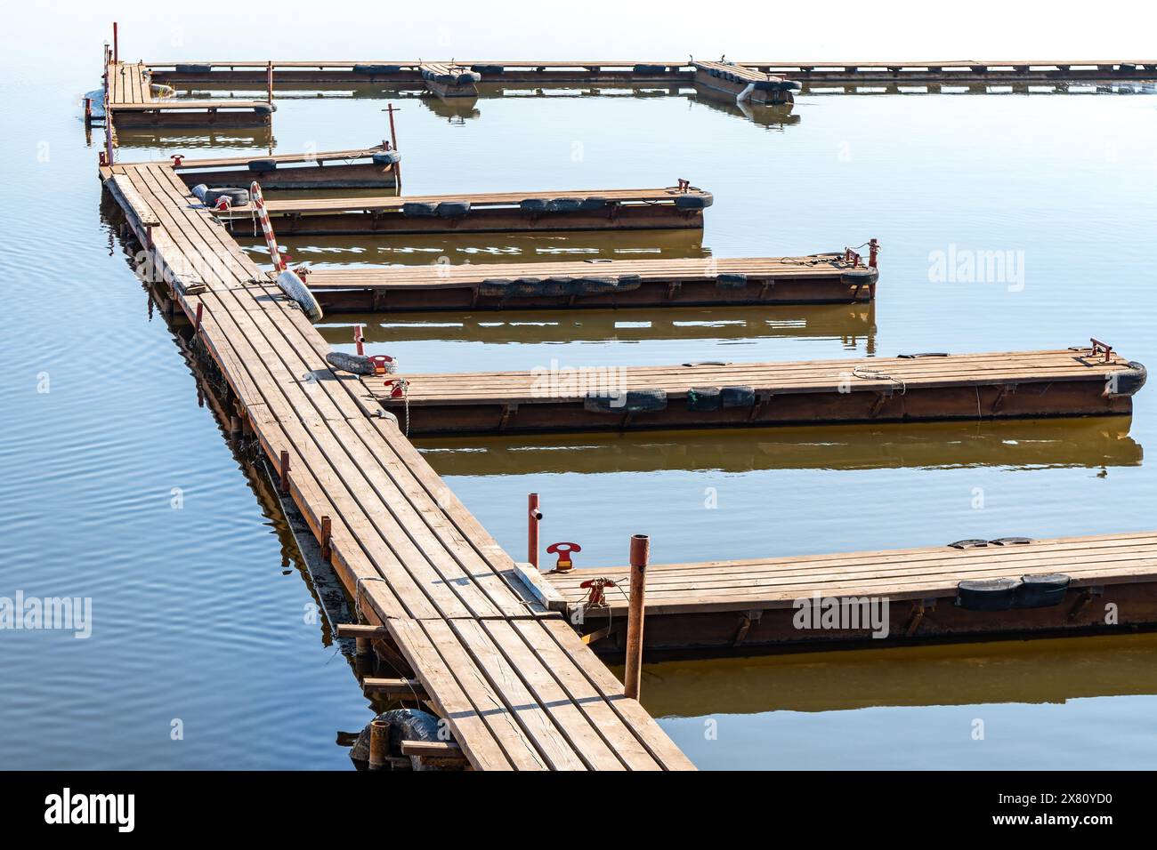 Empty wooden pontoon pier for fishing boats on tranquil river. Several ...