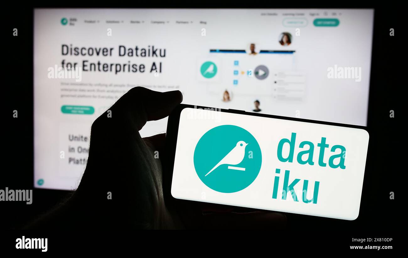 Person holding mobile phone with logo of American artificial intelligence (AI) company Dataiku ...