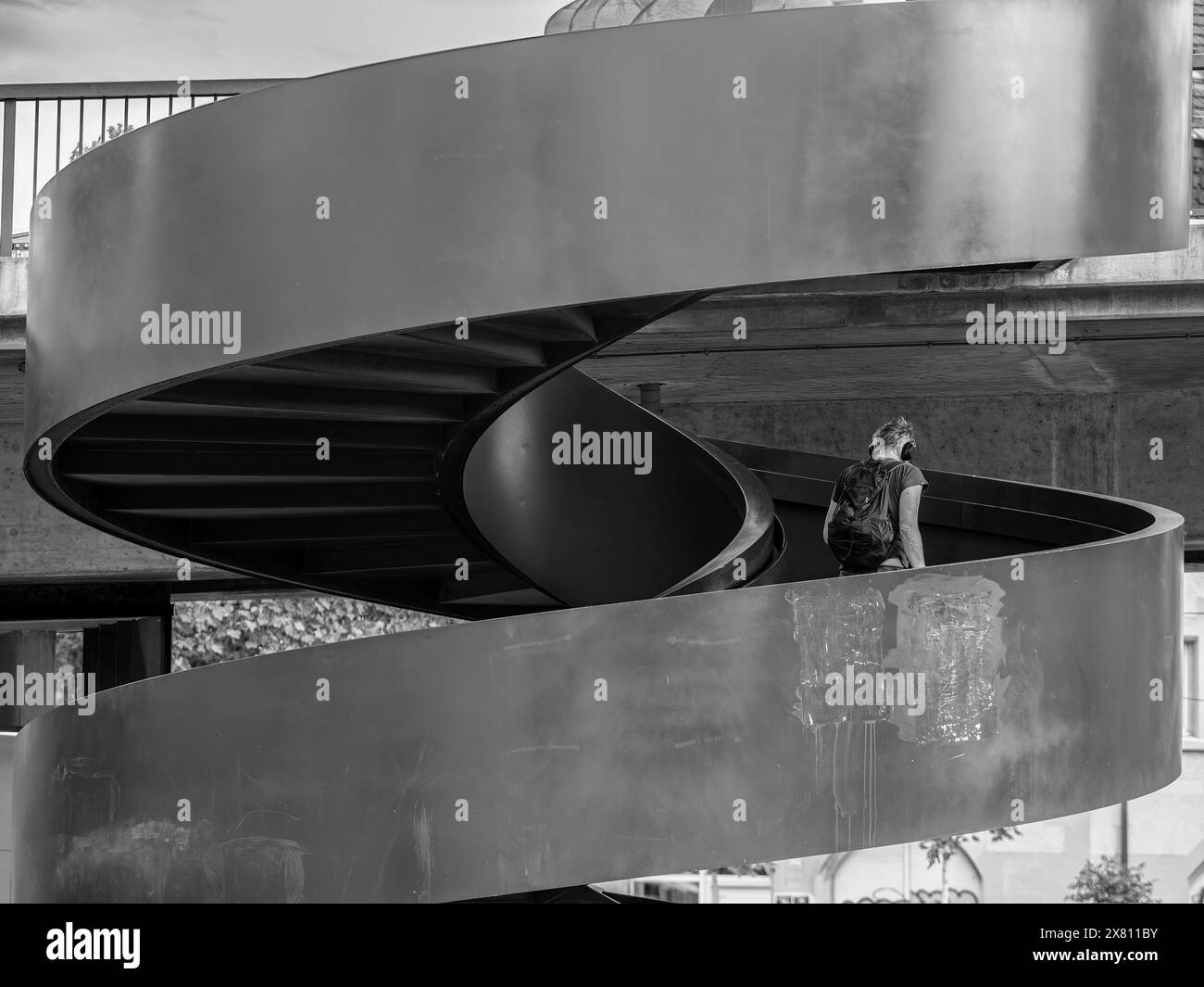 A modern spiral staircase with a person ascending, sleek design, urban ...