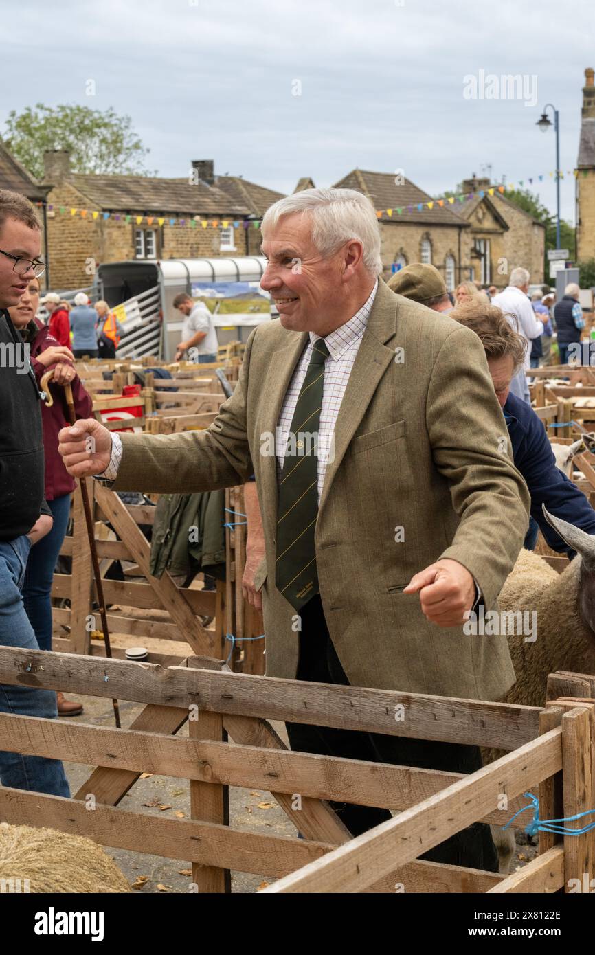 Mature male judge smiling, standing beside a wooden animal pen in the ...