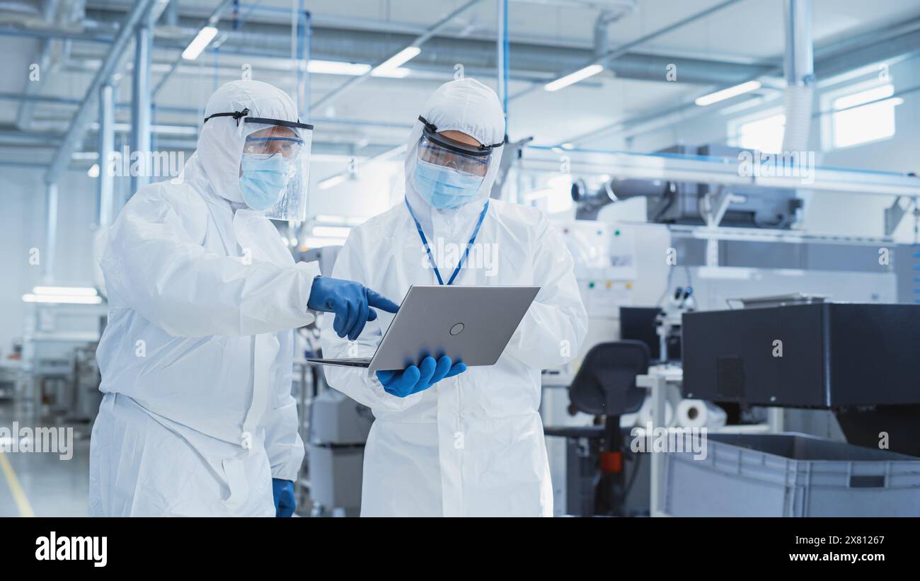 Two Scientists Walking in a Heavy Industry Factory in Sterile Coveralls ...