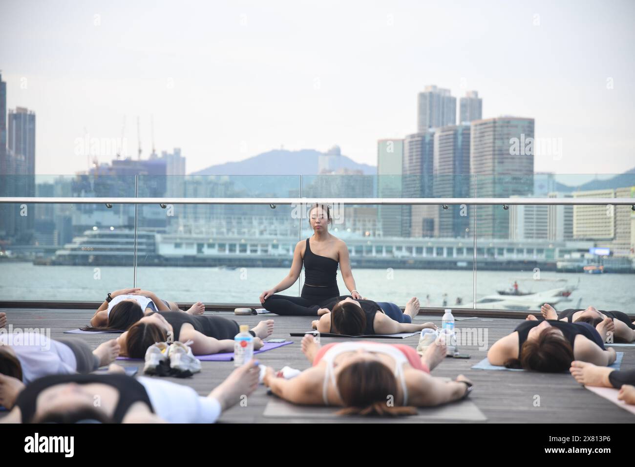 Yoga teacher and her students doing meditation outdoor in Wan Chai ...