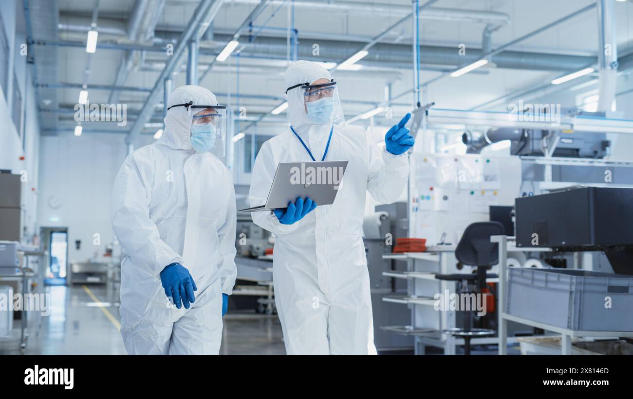 Two Scientists Walking in a Heavy Industry Factory in Sterile Coveralls ...