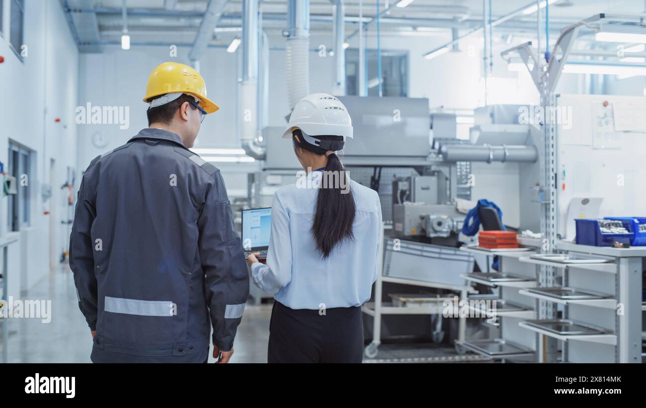 Back View: Two Heavy Industry Employees in Safety Uniforms and Hard ...