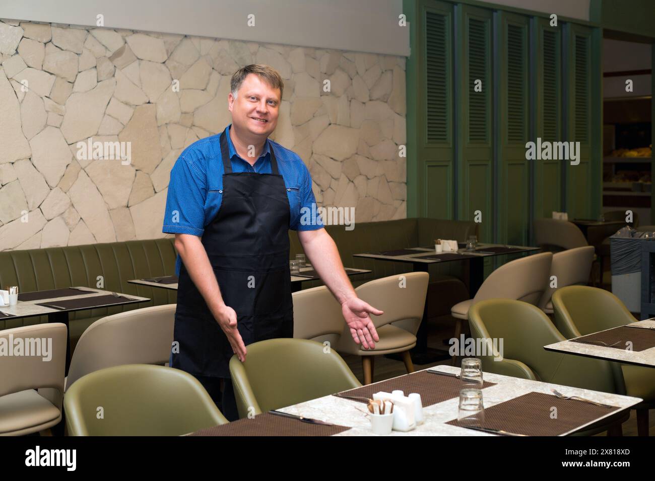 A polite waiter offers a seat for cafe guests Stock Photo - Alamy