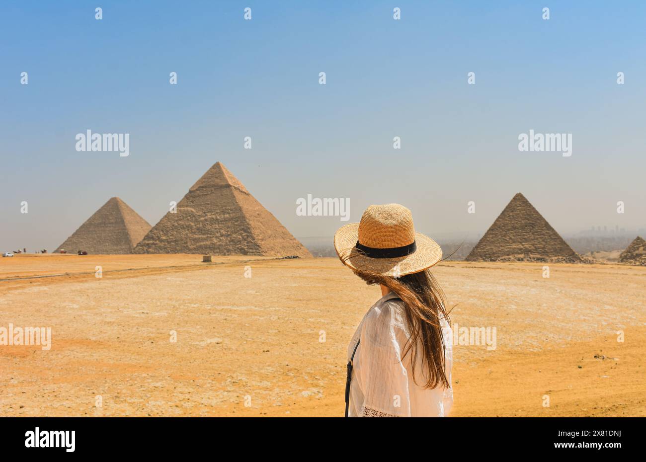 Back view of a woman wearing a hat, looking at the 3 great pyramids in ...