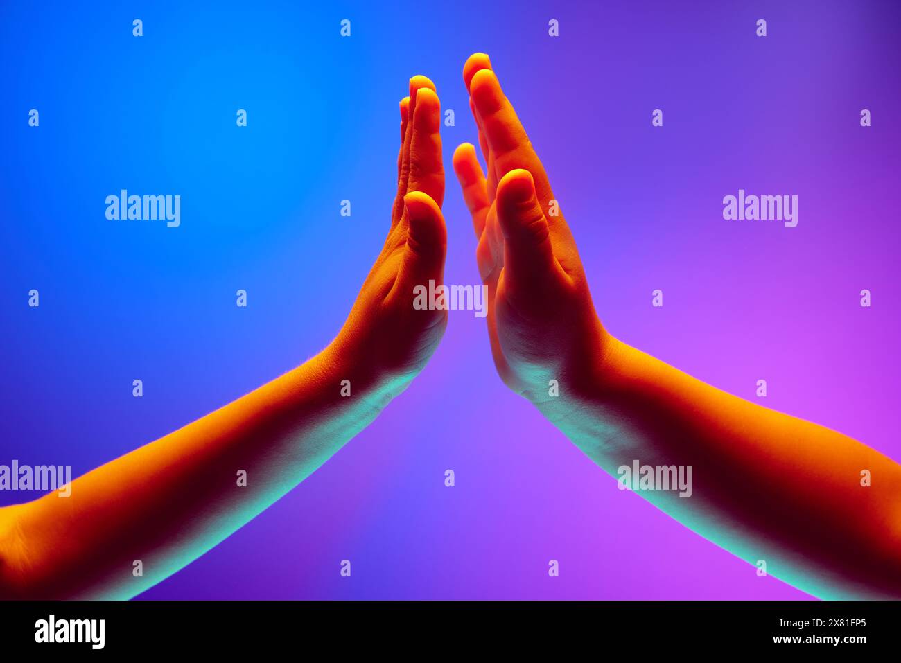 Two kids hands giving high five against multicolored background in neon ...