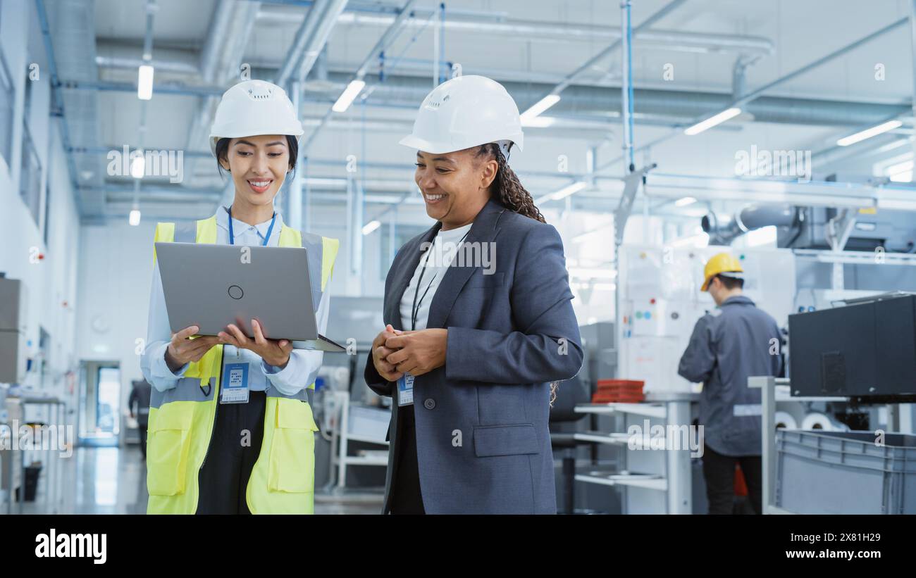 Portrait of Two Female Employees in Hard Hats at Factory Discussing ...