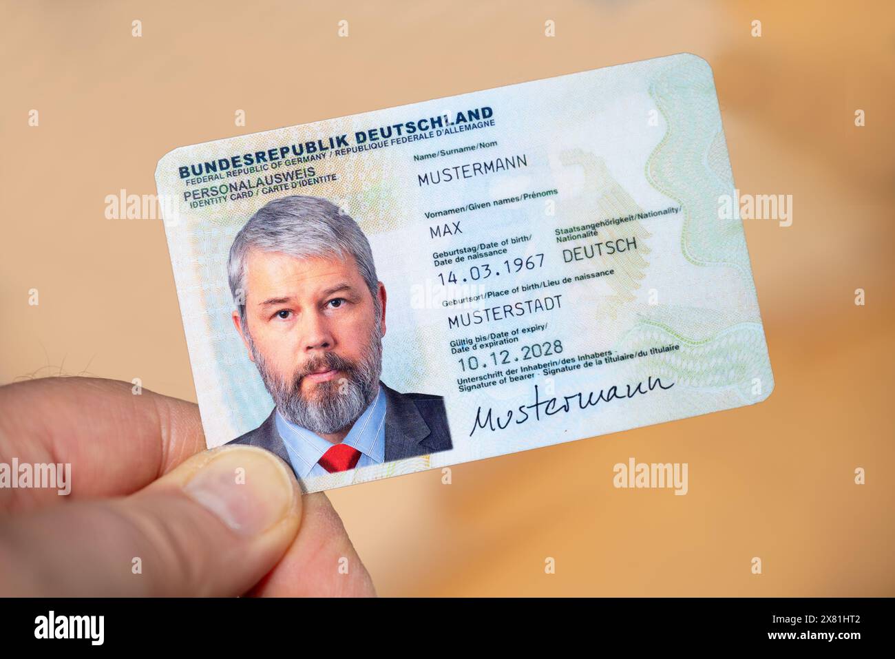 a hand holds a German identity card with a businessman around 50 years ...