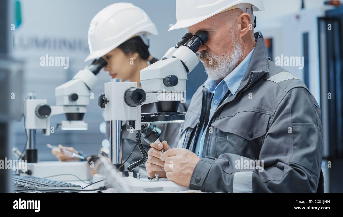 Middle Aged Industrial Scientist and Younger Asian Engineer Working at ...