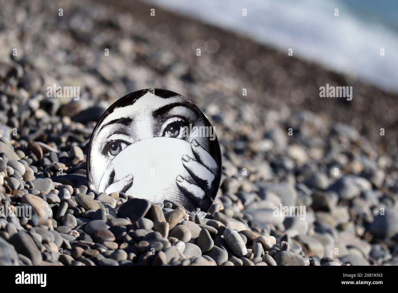 Fornasetti plate on the pebble beach, the face belongs to Italian opera ...