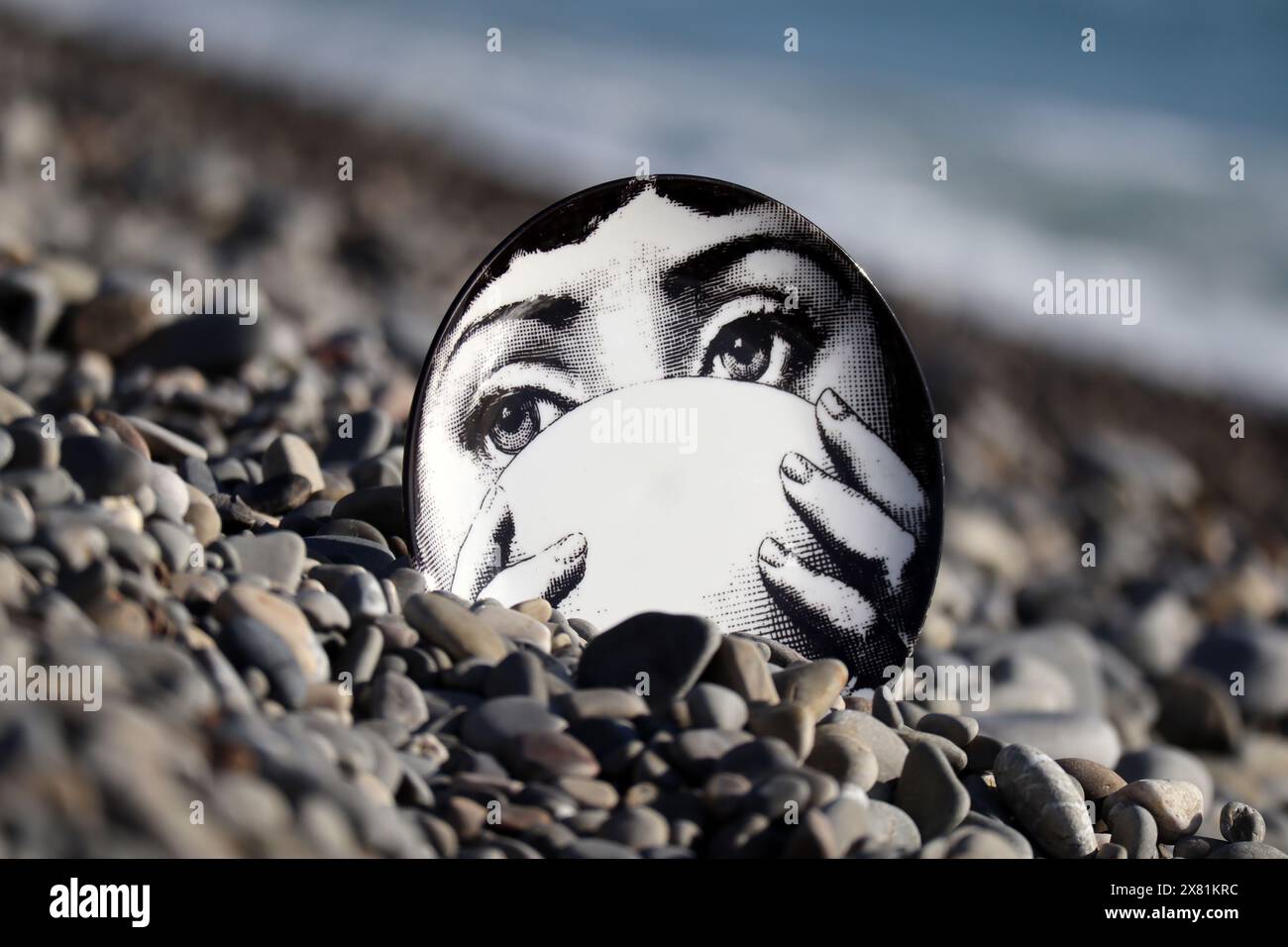 Fornasetti plate on the pebble beach, the face belongs to Italian opera ...