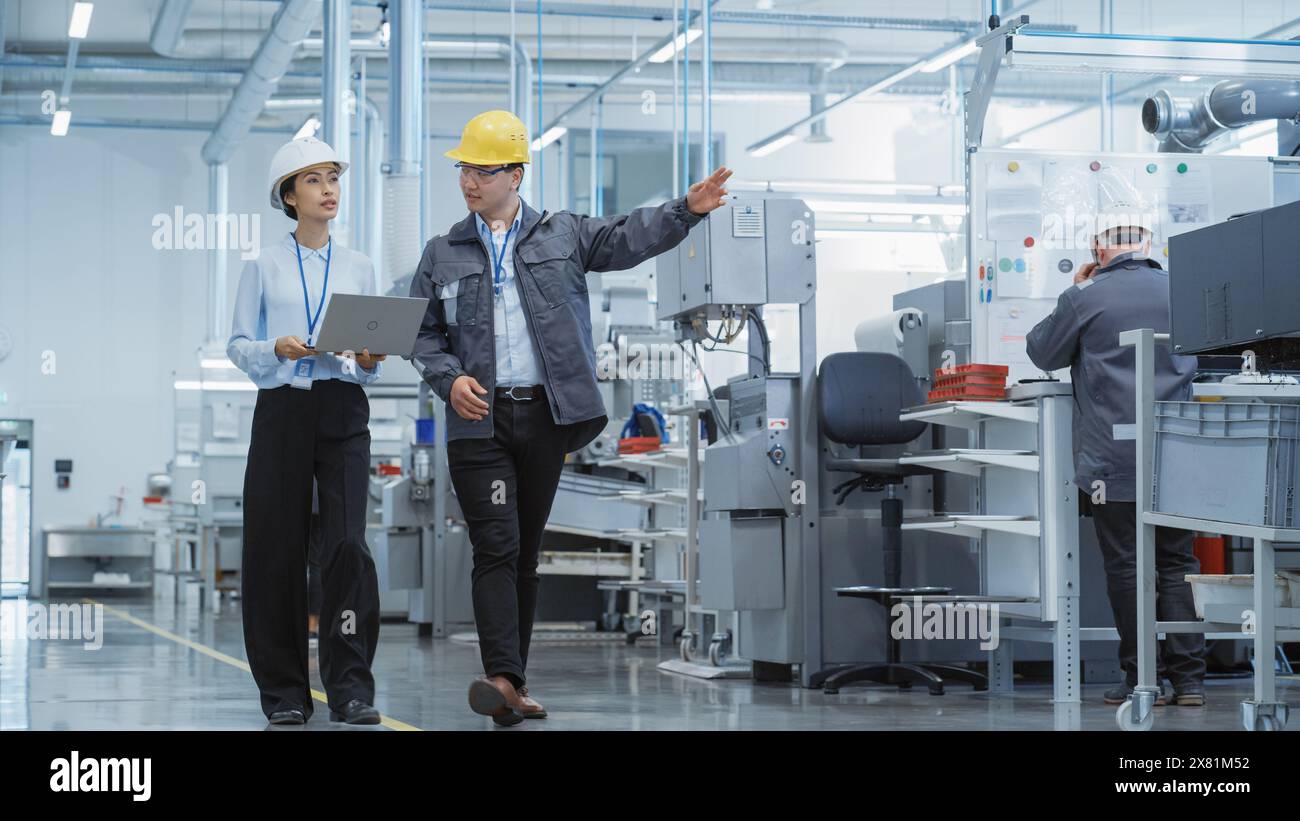 Two Young Asian Heavy Industry Engineers in Hard Hats Walking with ...
