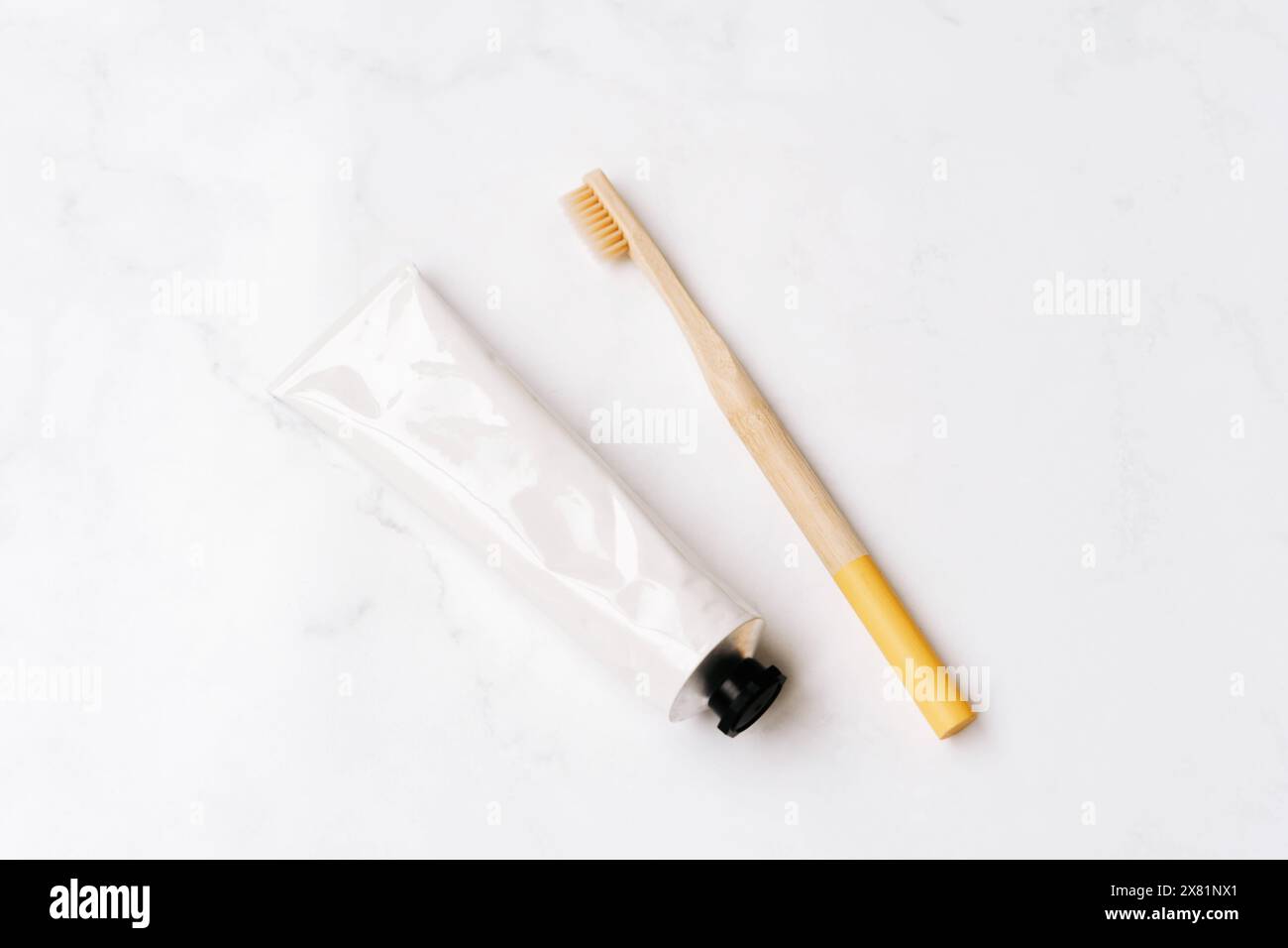Top view of white metal tube without label and toothbrush on white ...