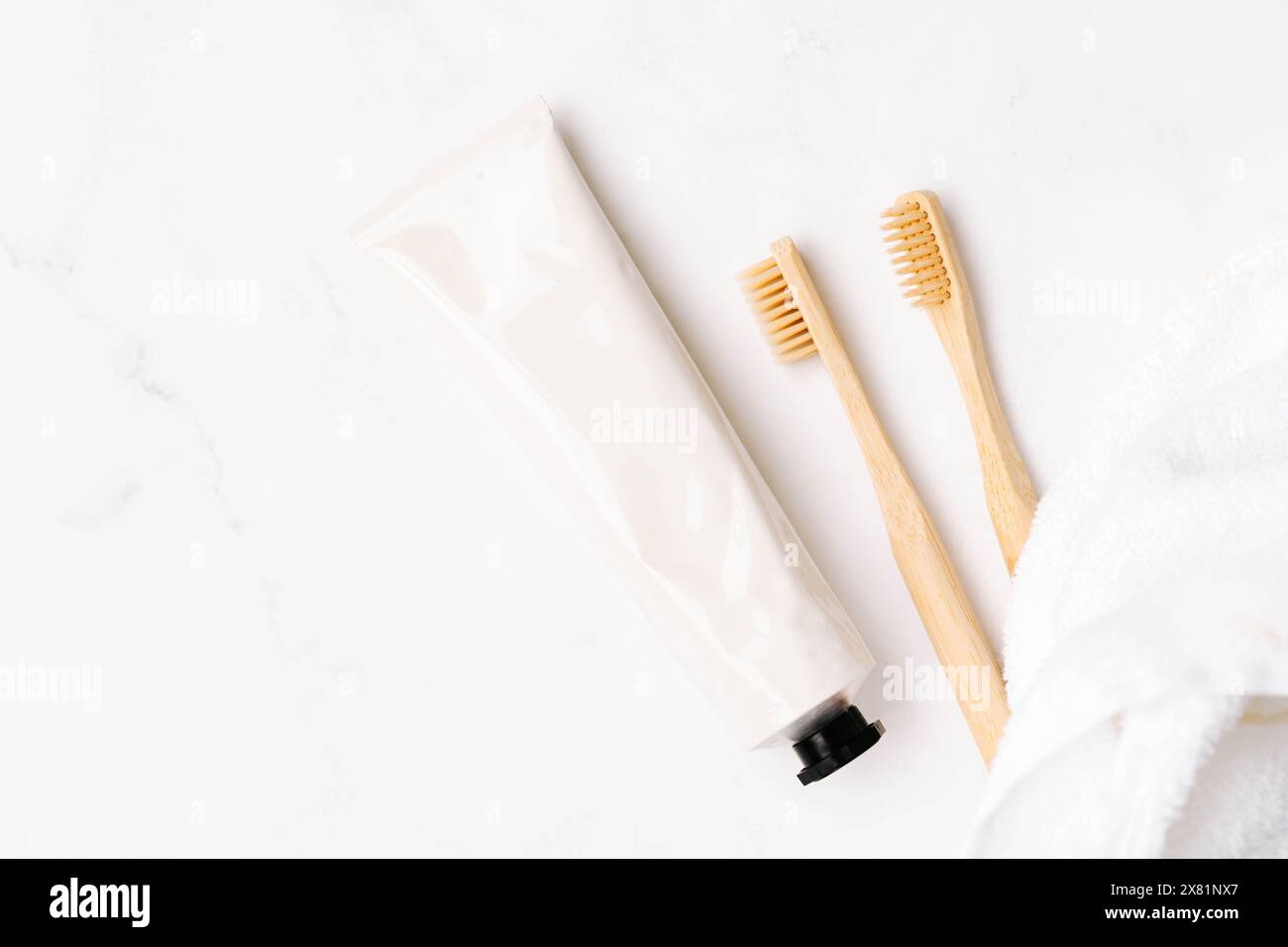 Top view of white metal tube without label and toothbrushes on white ...