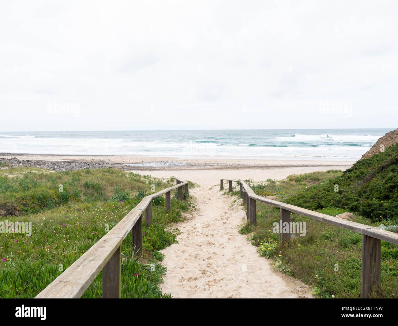 Wooden walkway over the sand of the beach dunes aimed at the empty ...