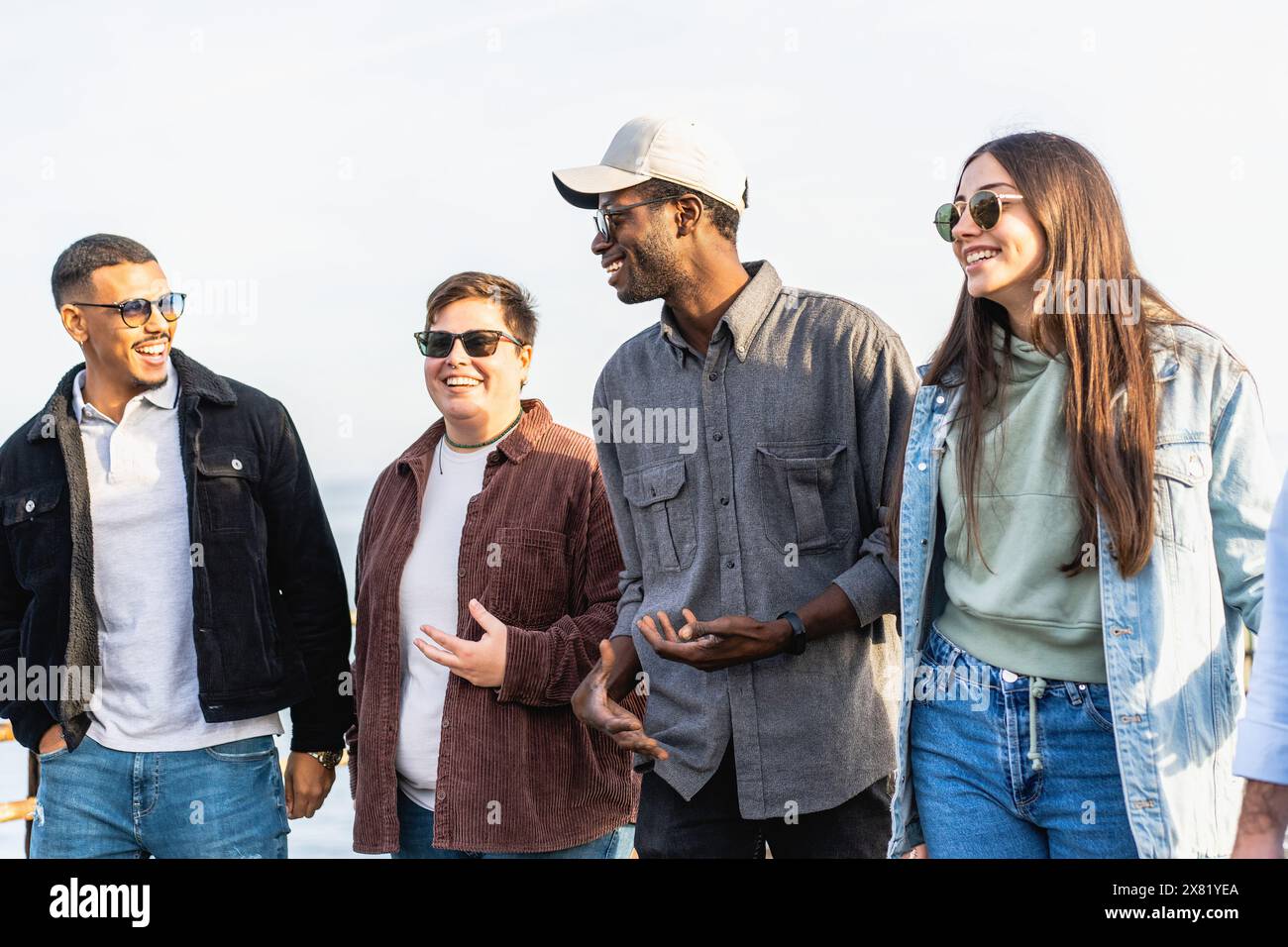 Multiethnic friends walking and laughing outdoors - enjoying a casual ...