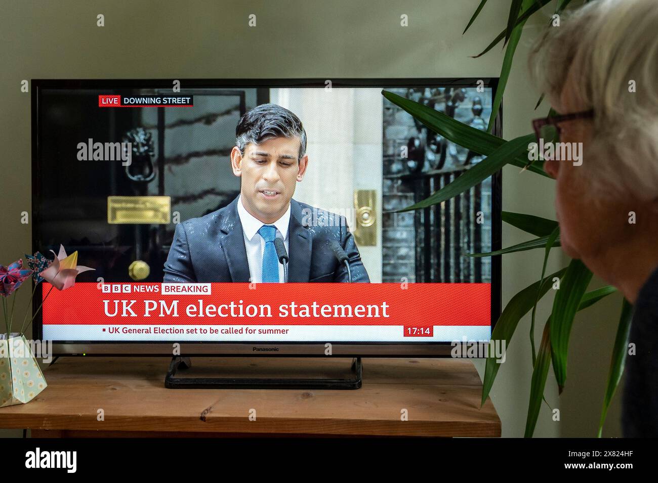 An older woman watching BBC TV news as Prime Minister Rishi Sunak announces the UK General ...