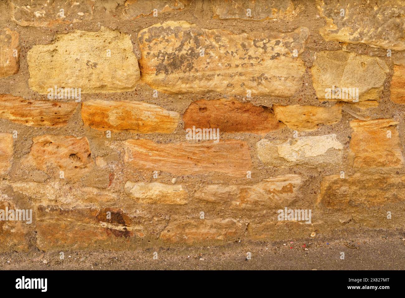 A weathered stone wall with patches of paint peeling off, showcasing a ...