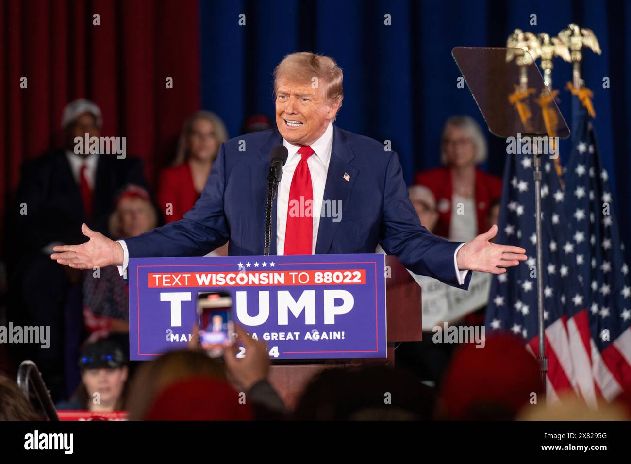 Donald Trump speaks on stage using a hand gesture at the sides of his ...