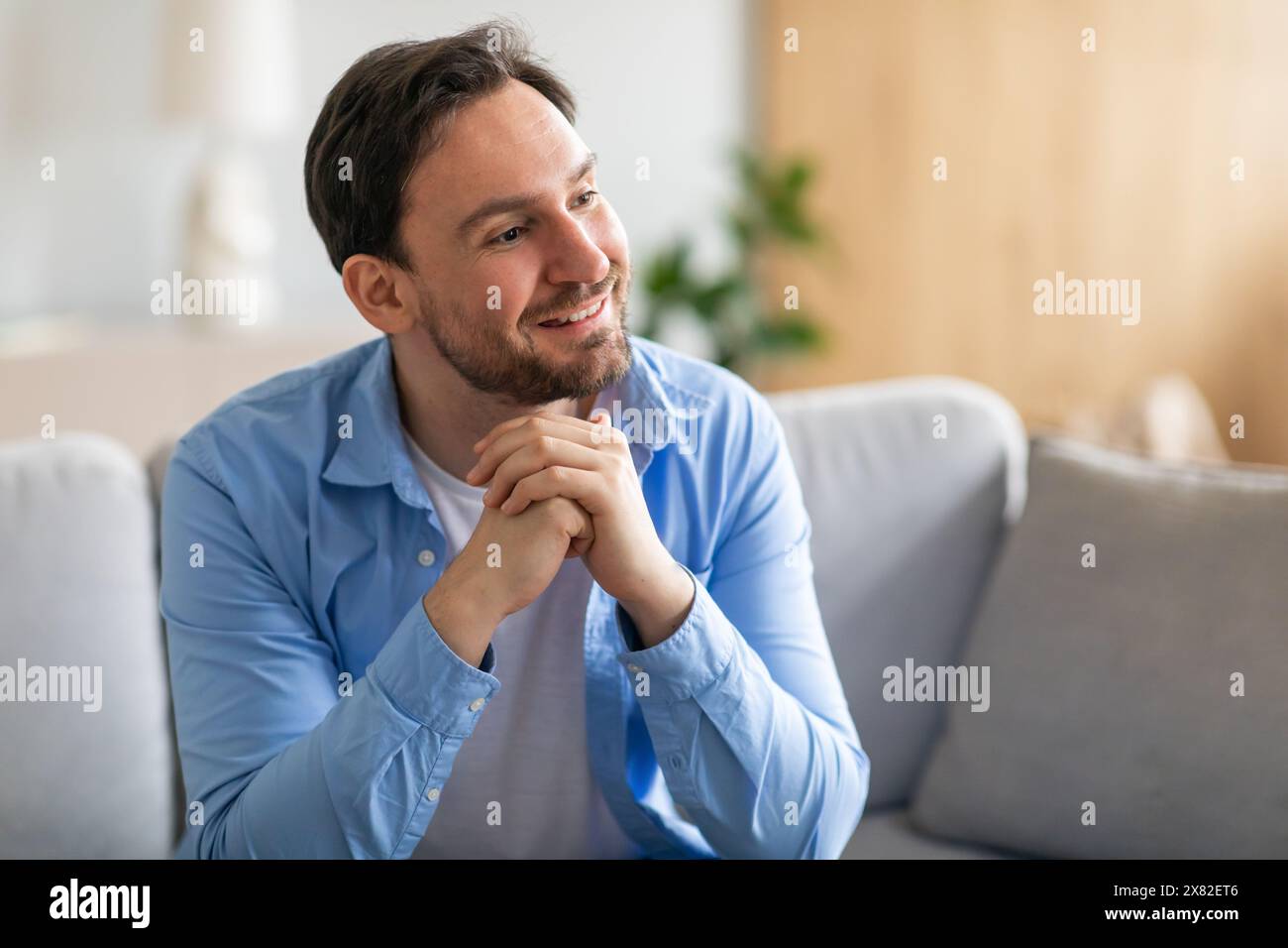 Smiling Man Sitting on Couch in a Well-Lit Living Room Stock Photo - Alamy