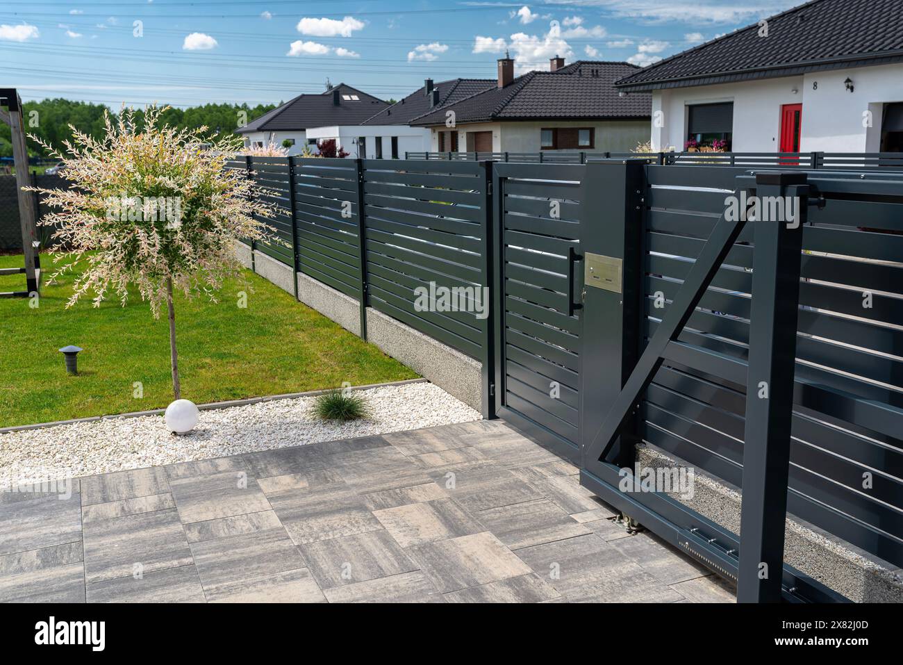 A modern panel fence in anthracite color, a visible sliding gate to the ...