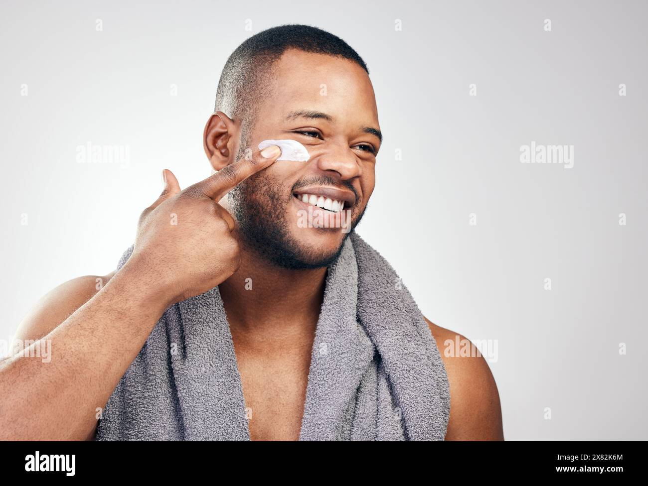 Black man, face cream and smile in studio for beauty with application ...