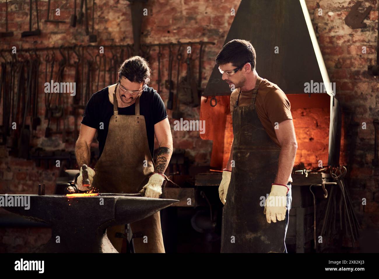 Men, blacksmith and metal teamwork in workshop for manufacturing steel ...