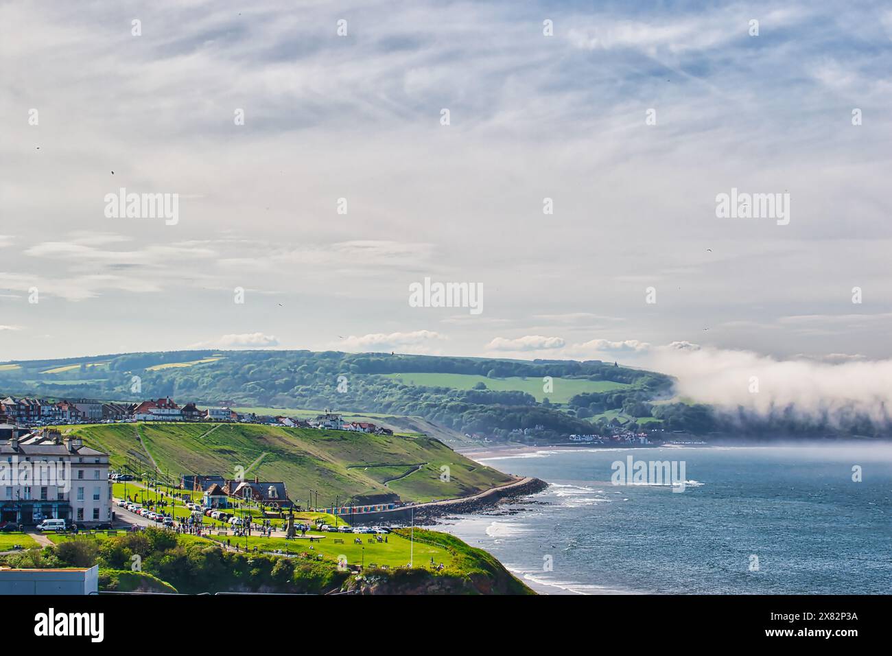 A scenic coastal view with green hills, a small town, and the ocean ...