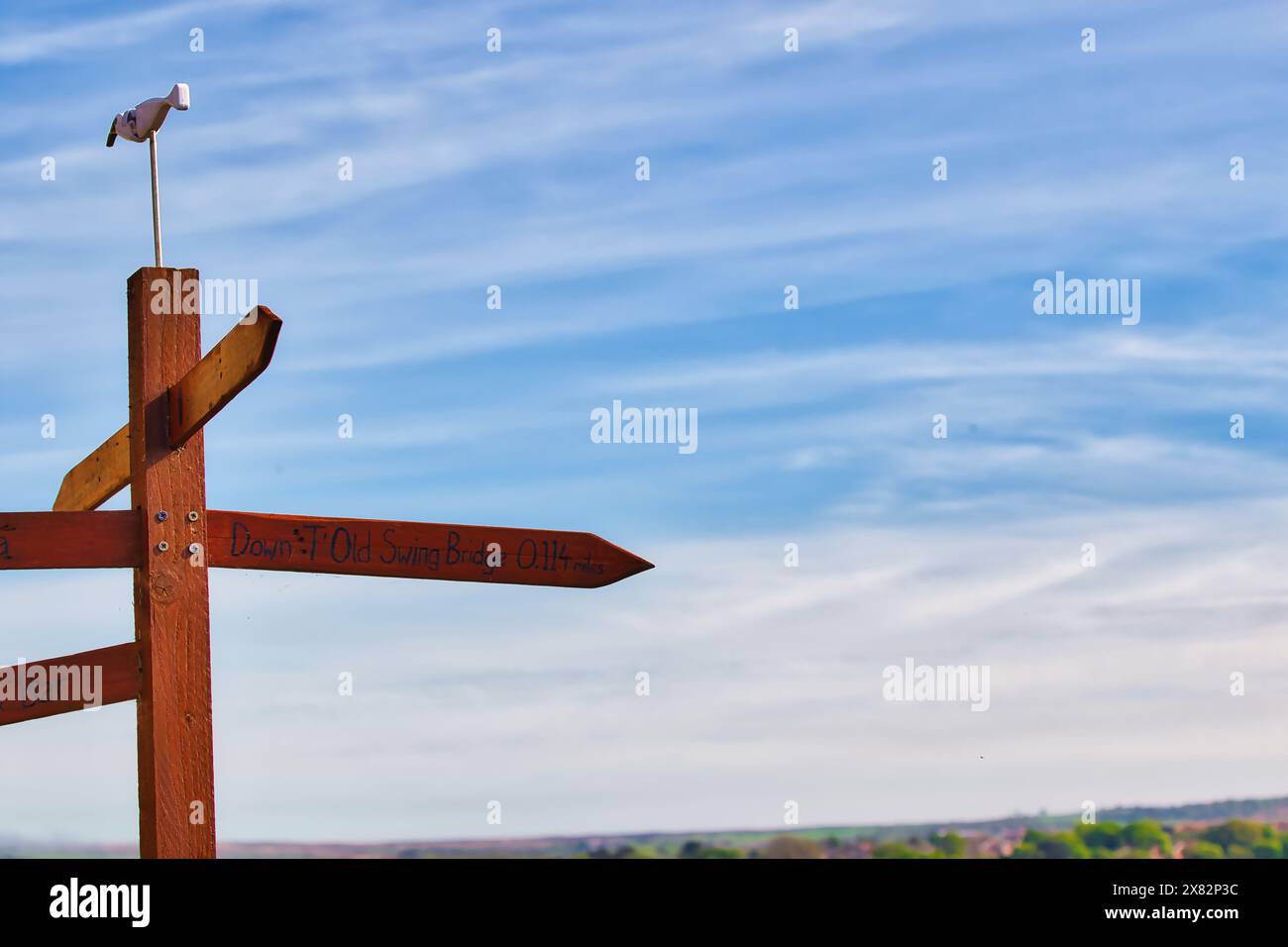 A wooden signpost with multiple directional arrows under a blue sky ...
