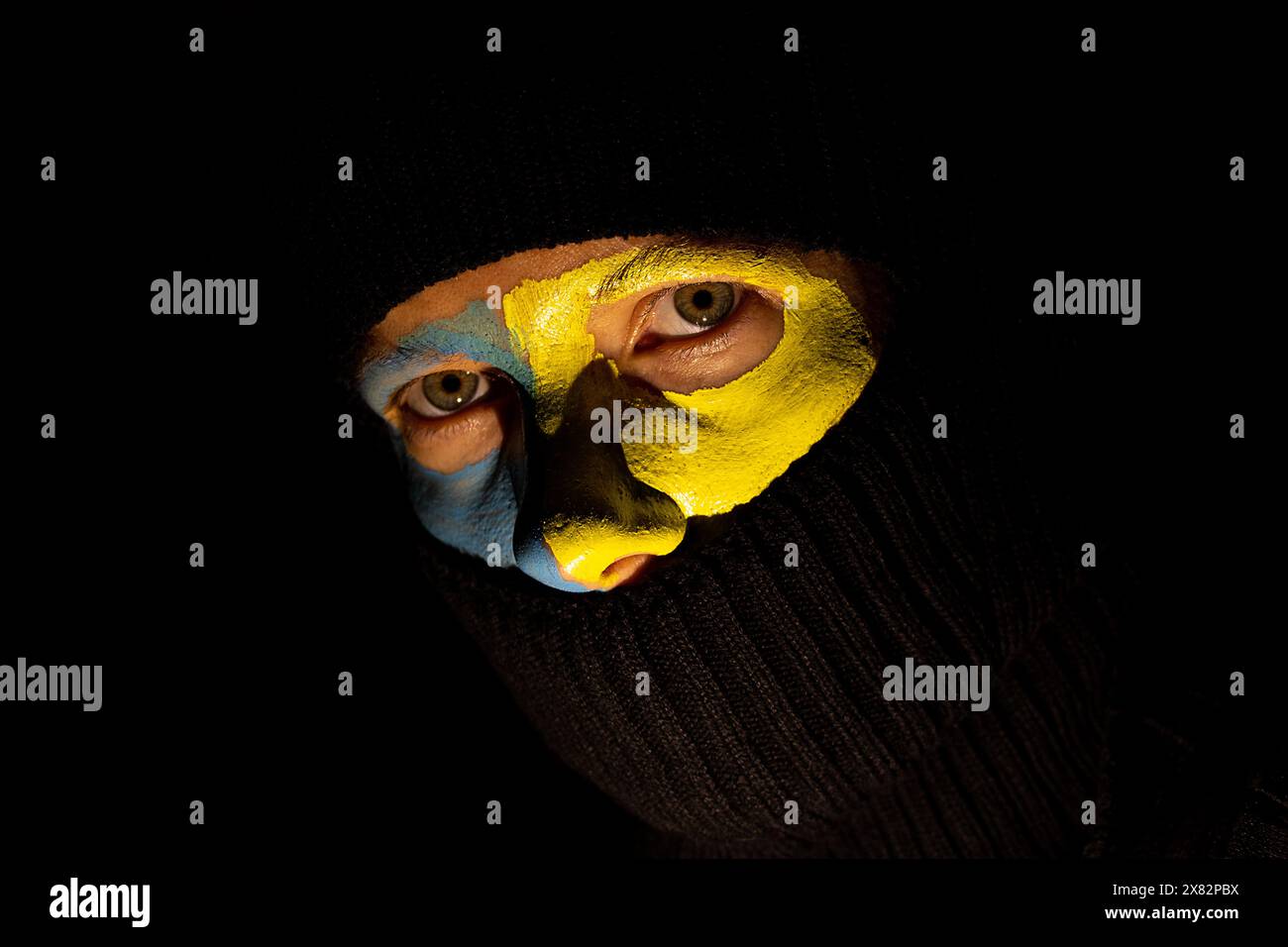 The face of a girl in a black balaclava and the flag of Ukraine is ...