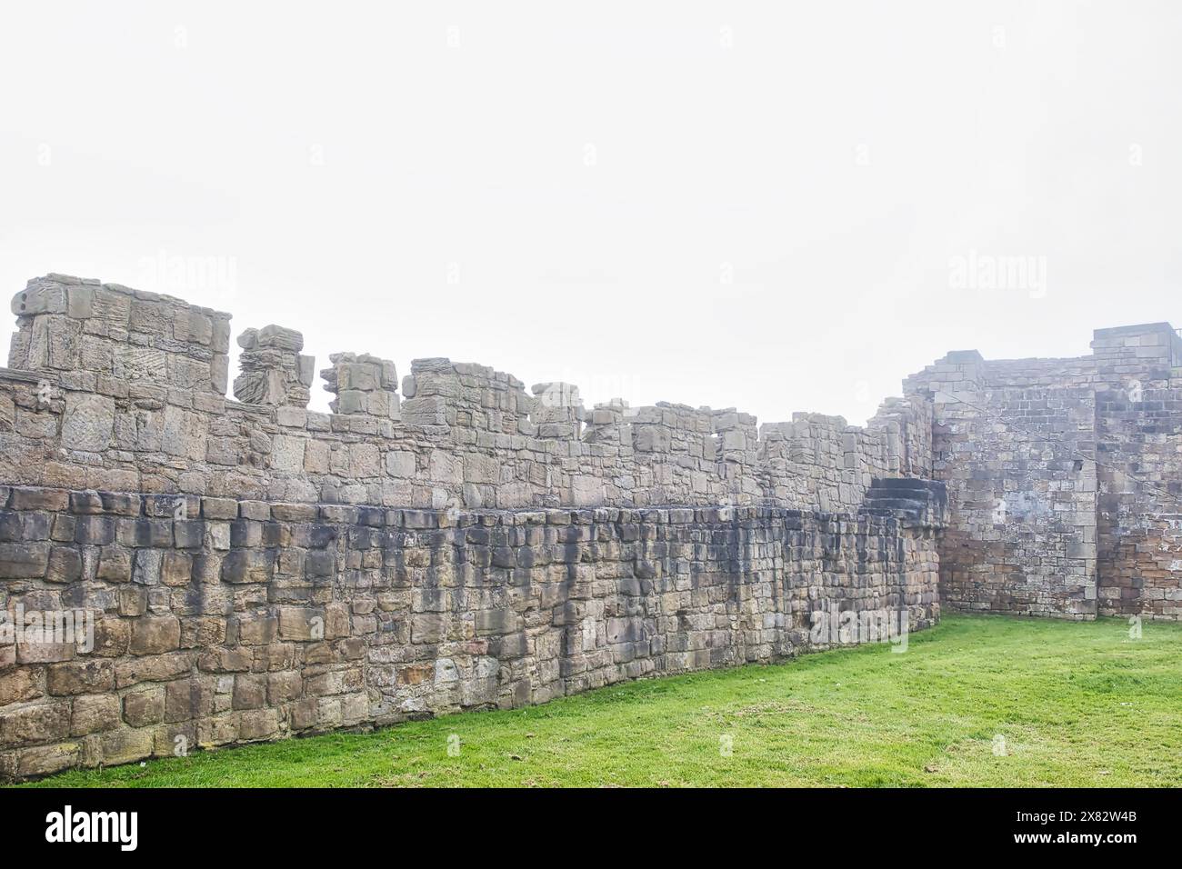 Ancient stone wall ruins with a grassy foreground and a foggy ...