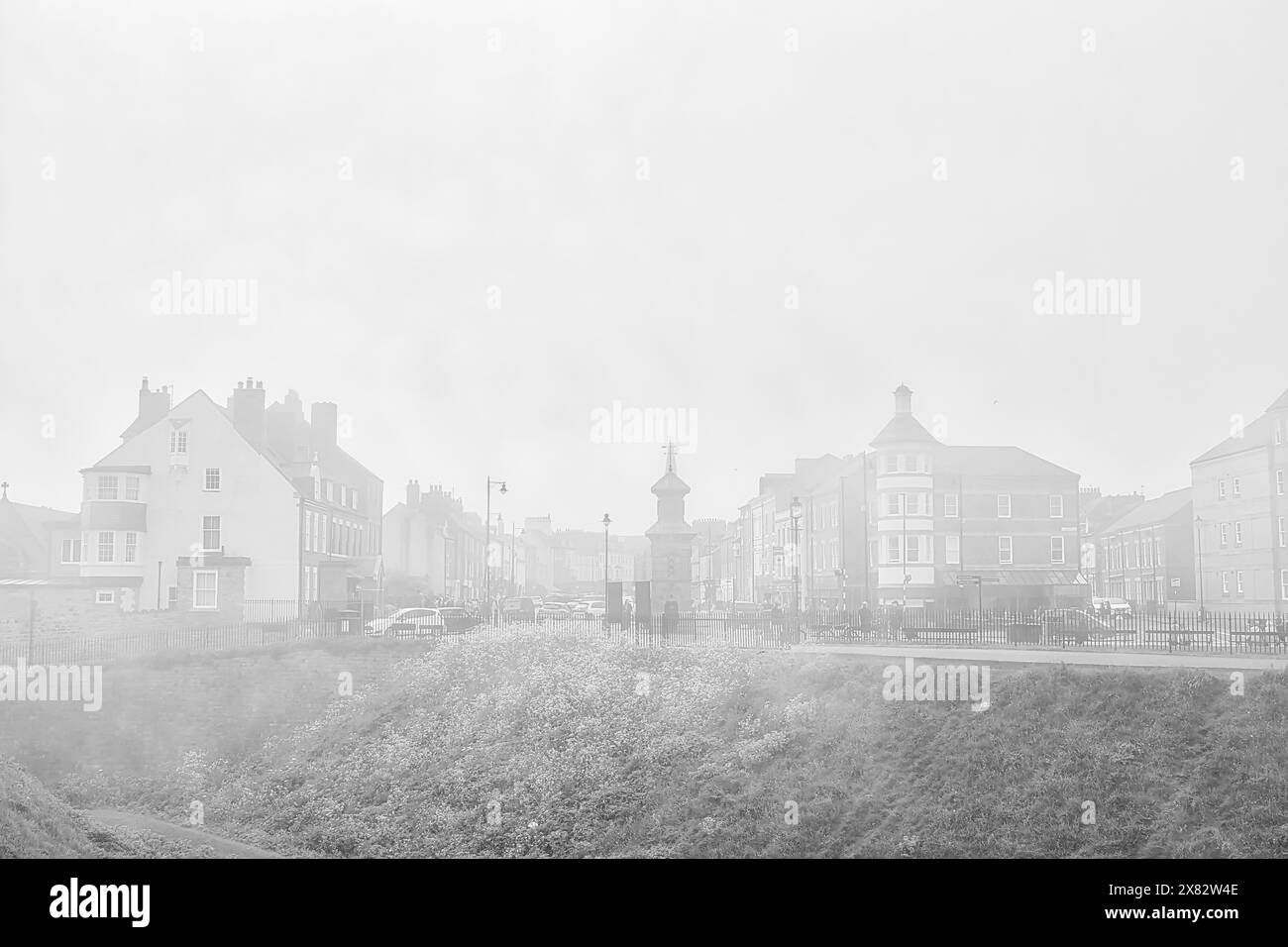 A foggy urban street scene with buildings and cars barely visible ...