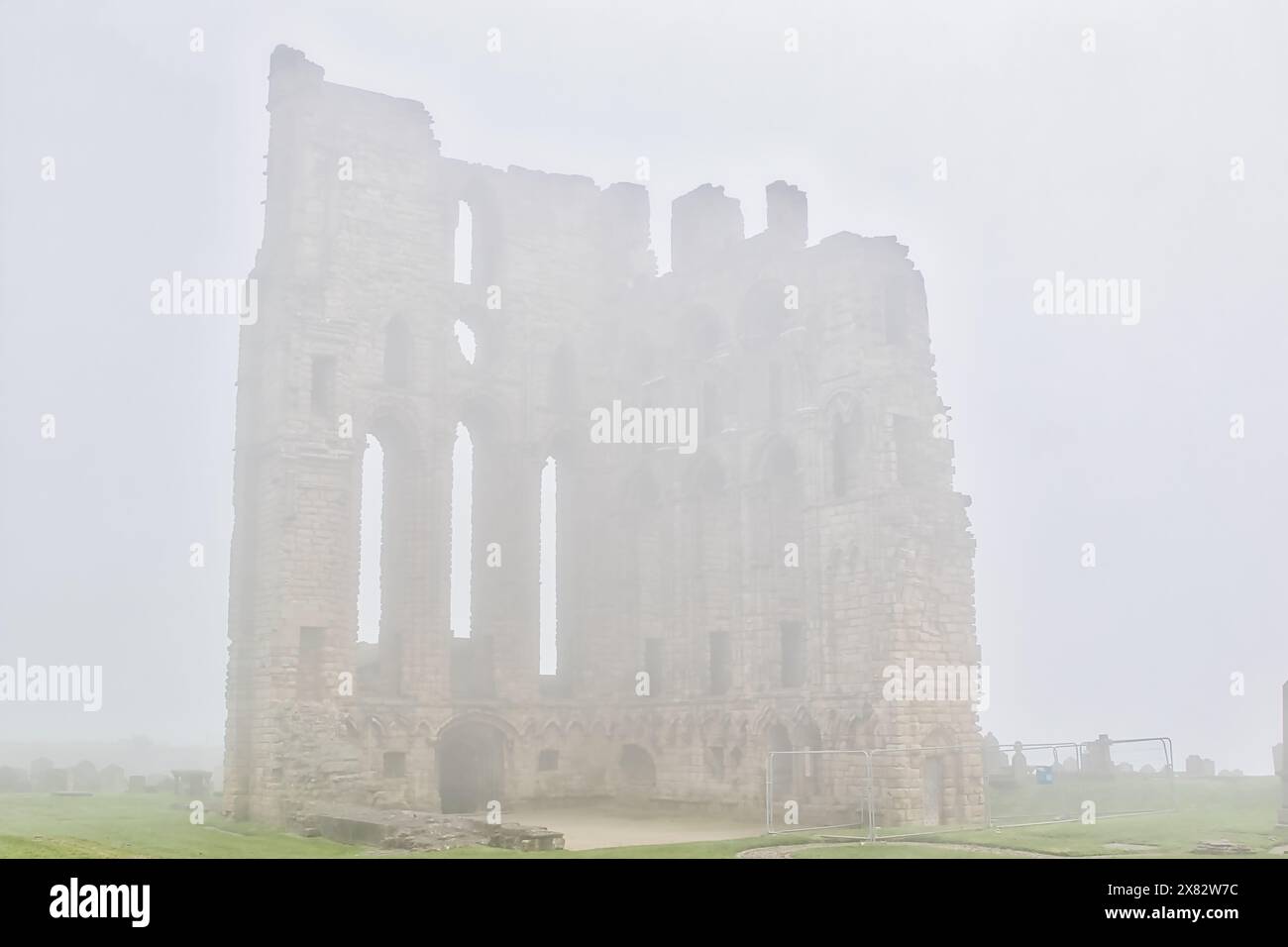 A foggy scene of an ancient stone castle ruin with tall, narrow windows ...