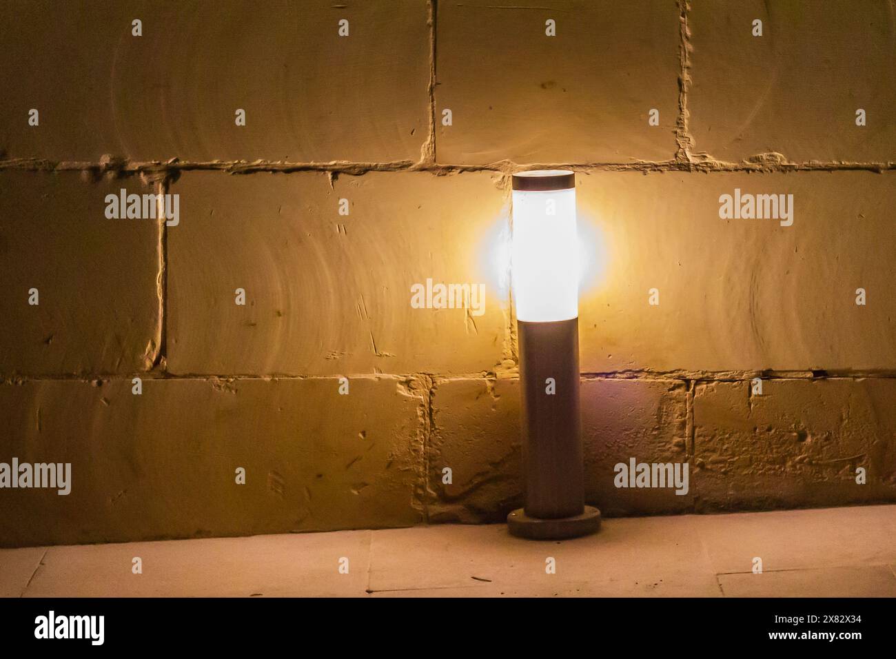 Illuminated yellow light bulb against outdoor wall at night Stock Photo ...