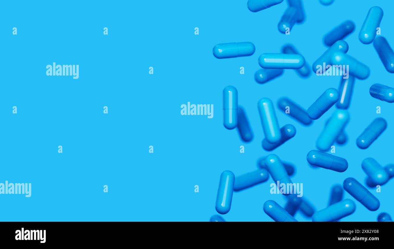Blue medicine capsules floatimg against blue backdrop with a place for ...