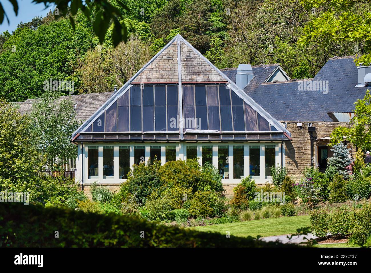 A modern house with a large triangular glass facade surrounded by lush ...
